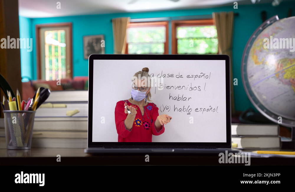 Dolly push in to laptop computer with female teacher wearing face mask ...