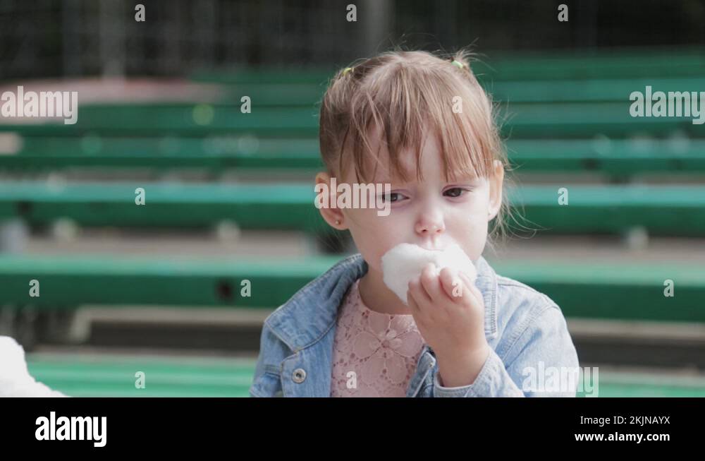Beautiful and happy little girl eating cotton candy on the bench Stock ...