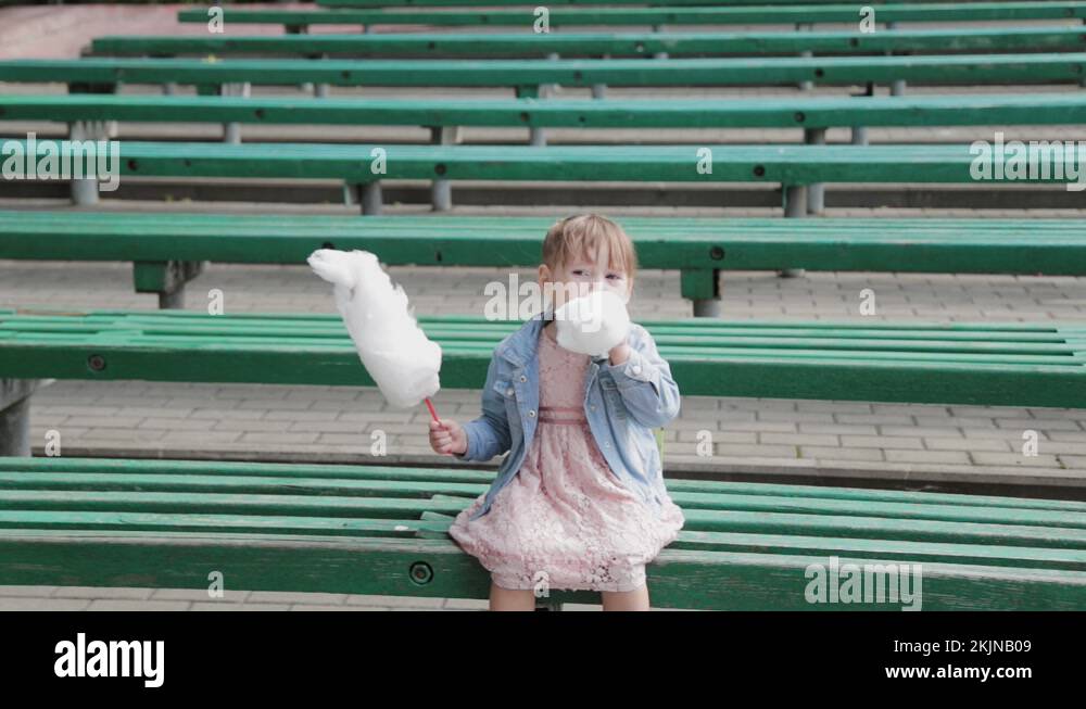 Beautiful and happy little girl eating cotton candy on the bench Stock ...