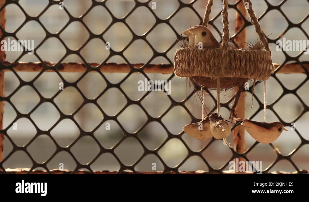 Artificial birds in the hanging nest with grid fence background Stock ...