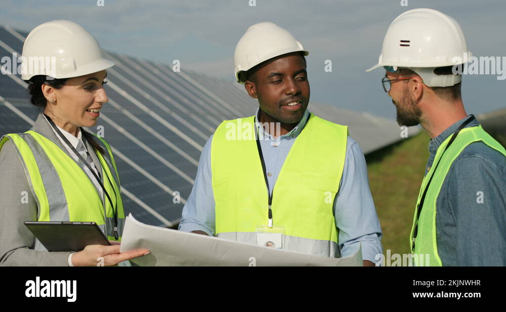 Three workers in special uniform discussing plan of work performed ...