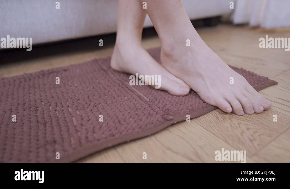 A young female barefoot step down and up from the couch, human body ...