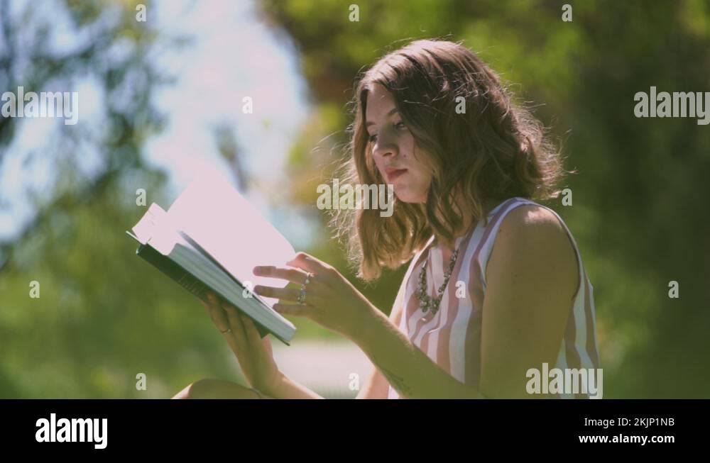 Concentrated lady with curly hair turns white book pages Stock Video ...