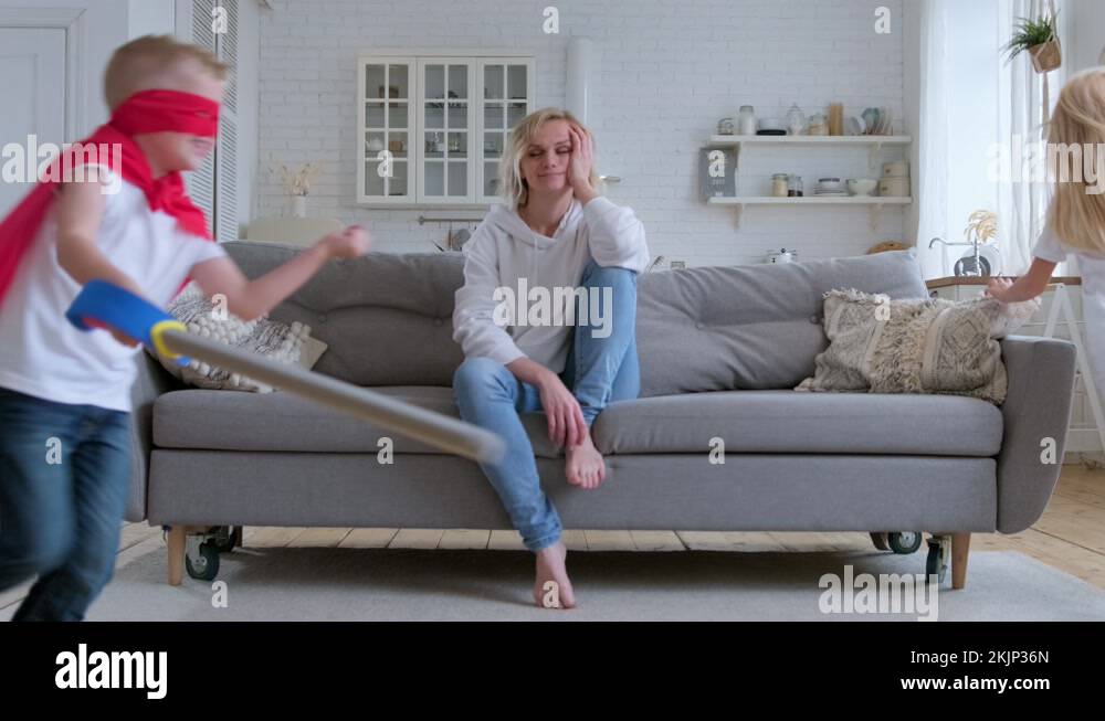 Calm balanced mother of two children is sitting on sofa, not nervous ...