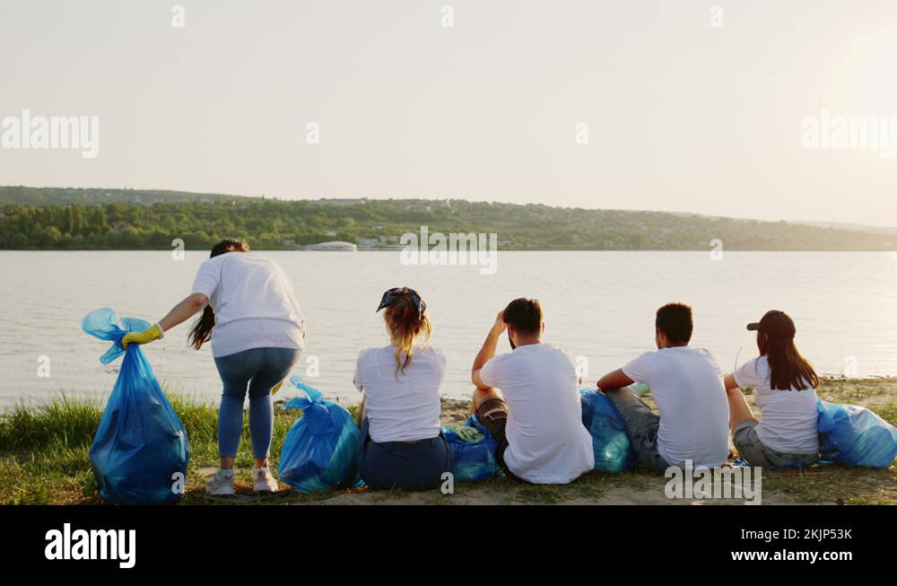 Young group of volunteers finish to cleaning up the rubbish then take a ...