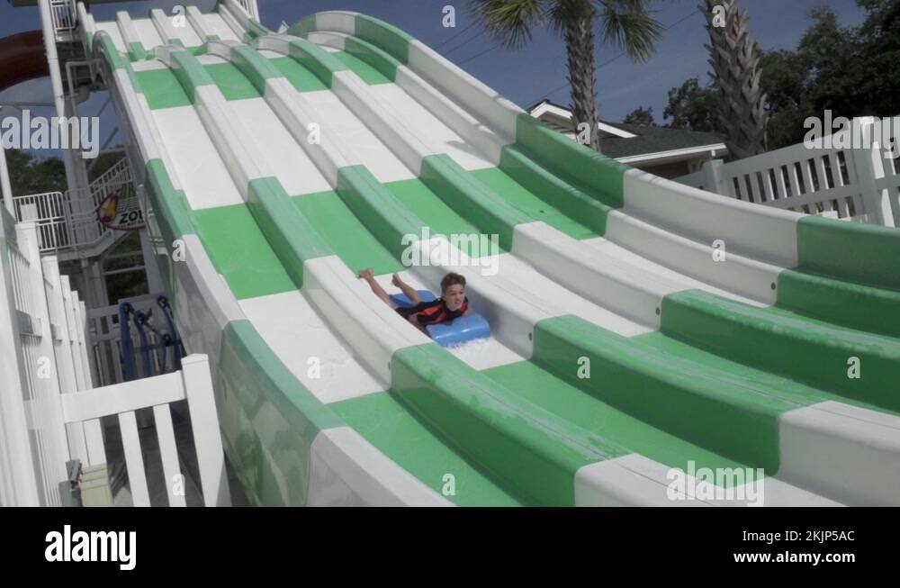 Children going down waterslide in slow motion at waterpark in summer ...