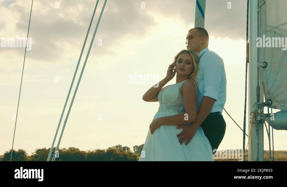 Newlyweds stand on a bow of a sailing yacht like in Titani. The bride put her Stock Video ...