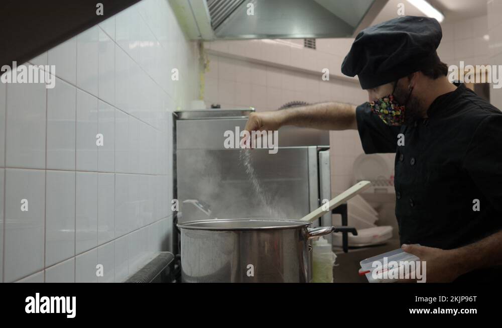 chef cooking with a medical mask and uniform in a restaurant kitchen ...