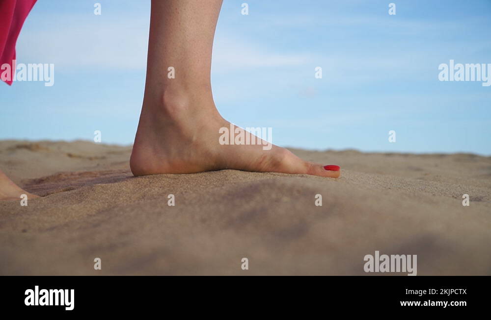 Low side view on slim female feet going along beach. Woman stepping at ...