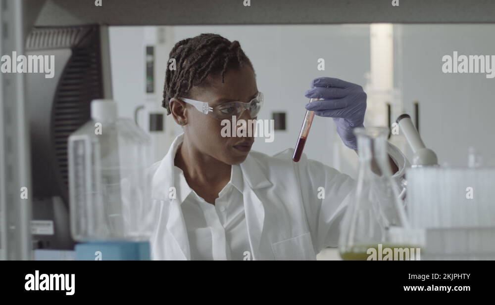 Female Laboratory Scientist Conducts Experiment in Science lab looking ...