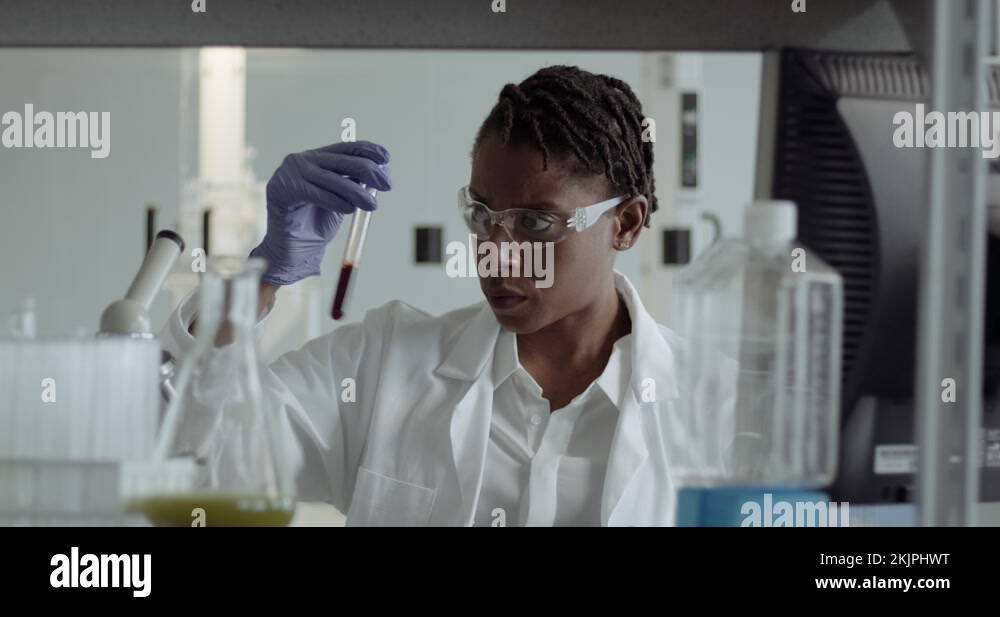 Female Laboratory Scientist Conducts Experiment in Science lab looking ...