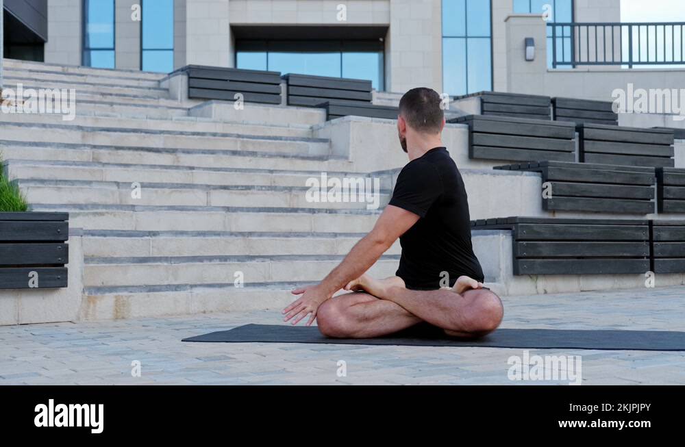 Man athlete practices yoga exercises, stretches, lotus position ...