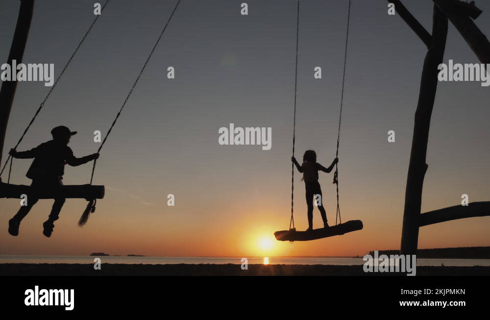 Silhouette two happy children friends sway on swings, summer carefree ...
