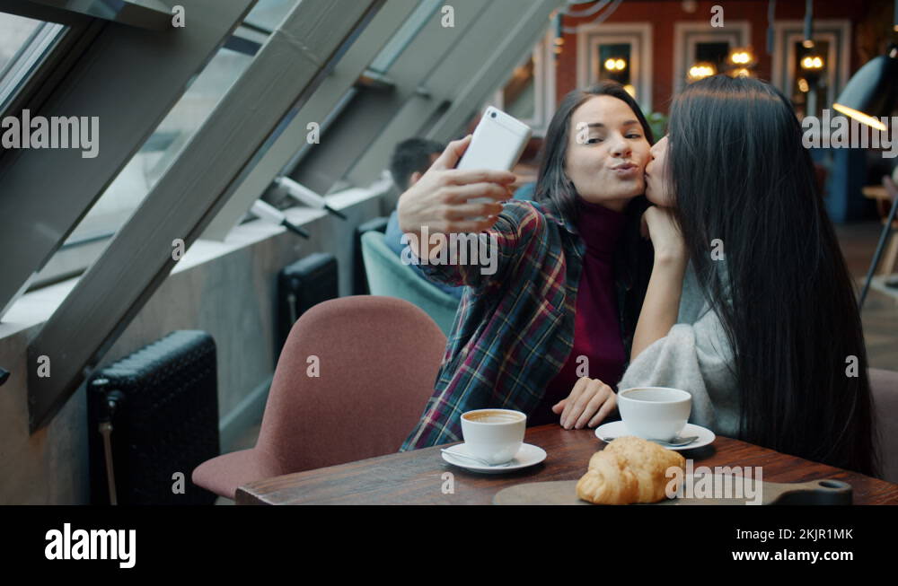 Charming young ladies taking selfie with smartphone camera posing ...