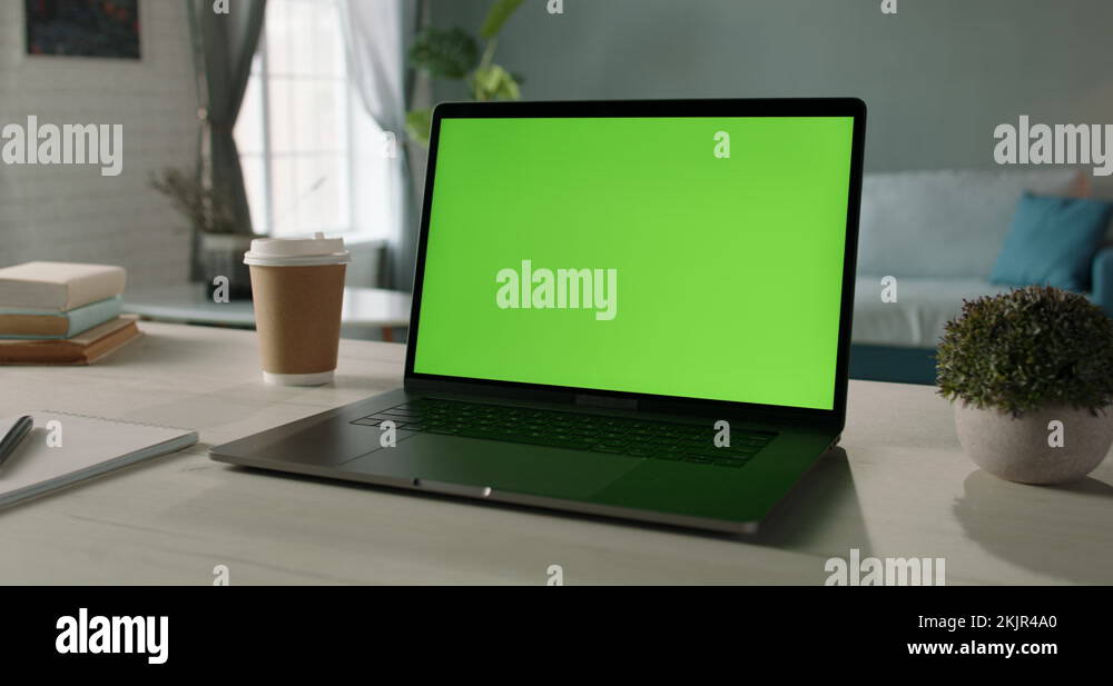 Modern laptop with mock up chroma key green screen st on desk of living ...