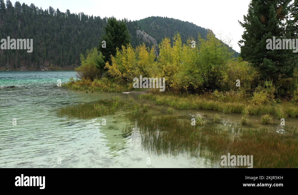 Rotating over Cliff Lake revealing camper on shoreline at campsite ...