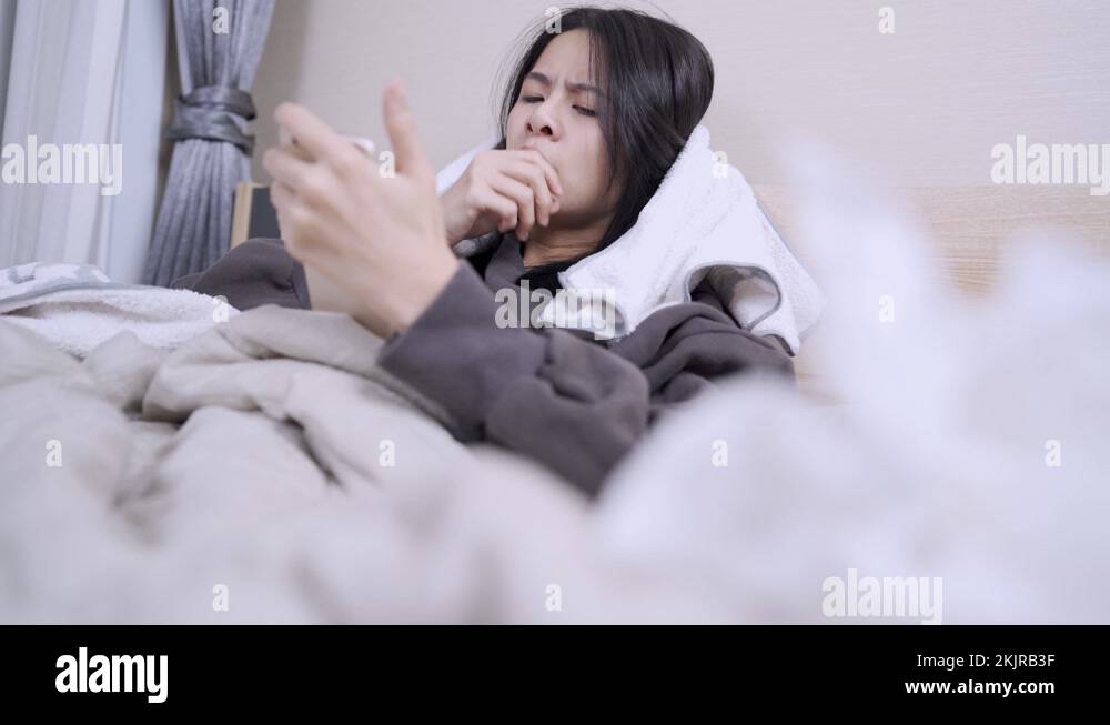 asian sick woman lying down inside blanket sheets while having fever on ...