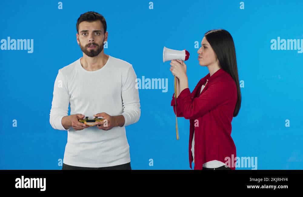 Angry woman shouting at her husband while playing video games with a ...