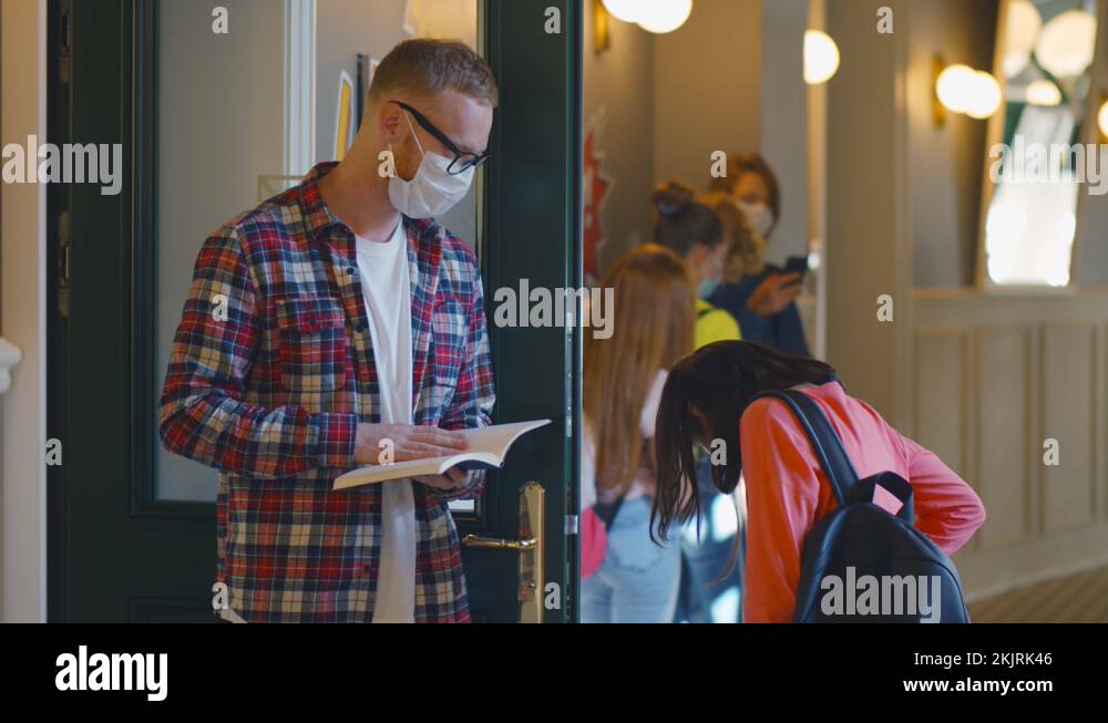 Young teacher standing at school entrance not letting students in ...