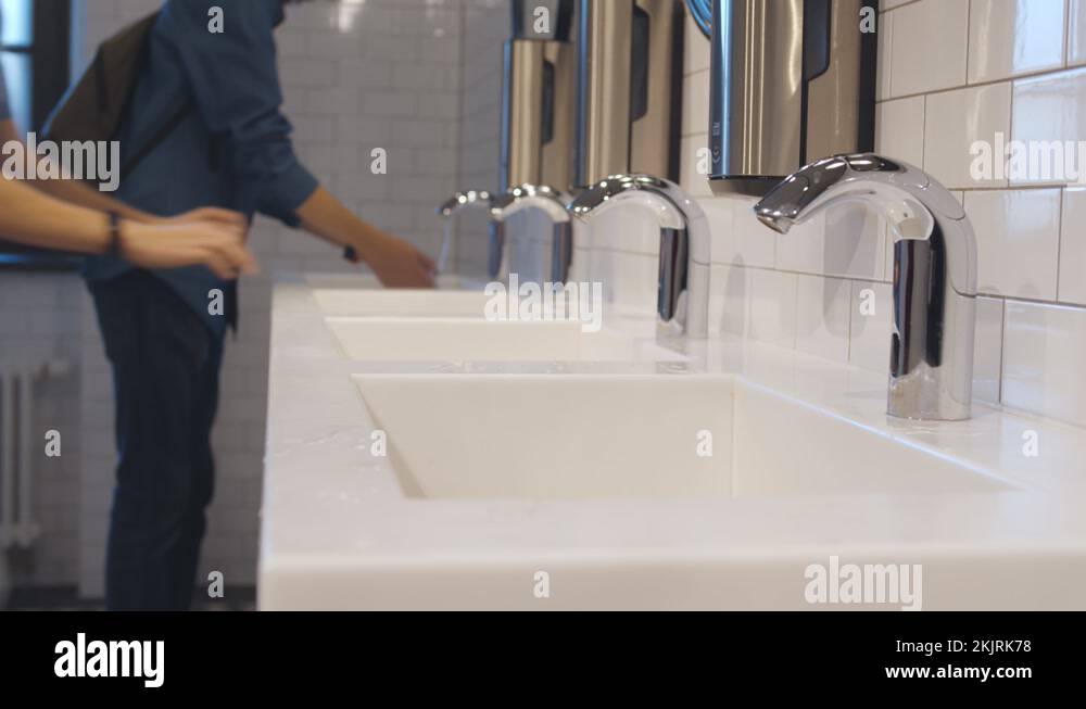 Close up side view of diverse school pupils washing hands in lavatory ...