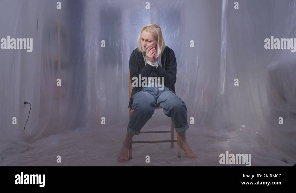 Female hostage sitting on a chair in a room with her mouth taped shut ...