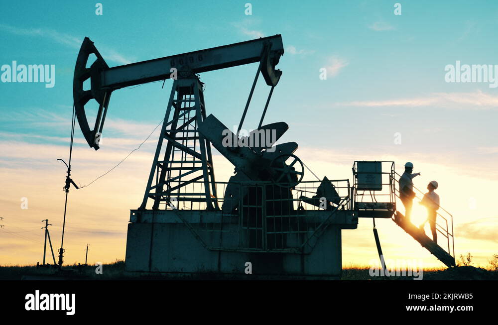 Engineers are standing on the oil pumping unit and talking Stock Video ...