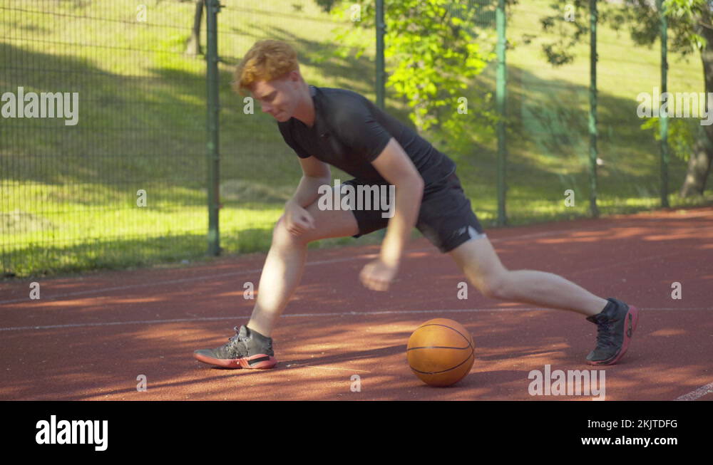 Wide shot portrait of basketball player stretching legs on outdoor ...