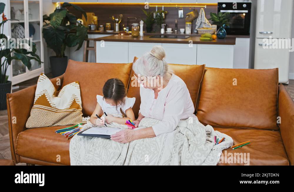Grandma and granddaughter drawing with felt-tip pens on sheet of paper ...