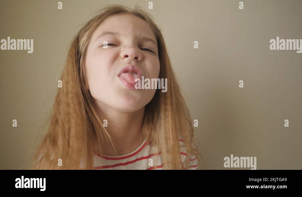 Small female child sticking her tongue out and turning aside indoor ...