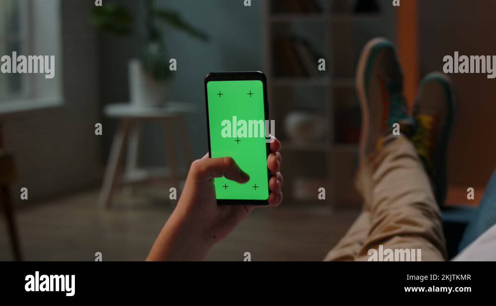 Man lying on couch using smartphone with chroma key green screen at night Stock Video Footage ...