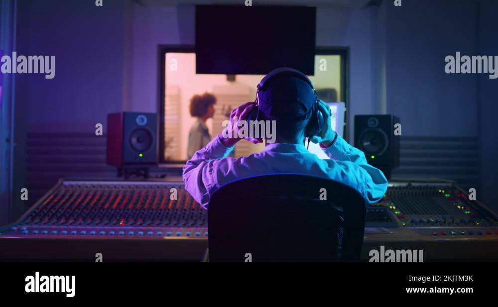 Back view of producer recording song with african female singer in ...