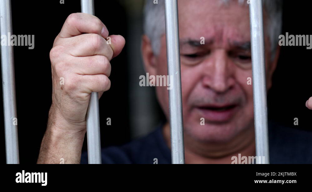 Imprisoned older man behind bars crying Stock Video Footage - Alamy