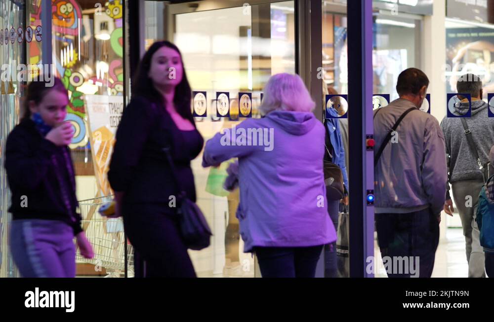 People enter and exit through revolving glass doors of mall. Shoppers ...