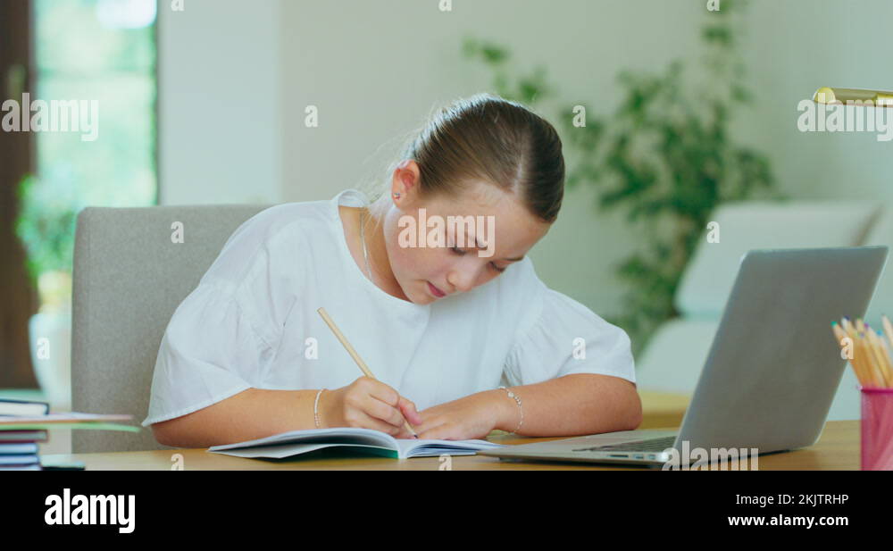 Cute teen girl at the desk, with laptop, doing homework, checking tasks ...