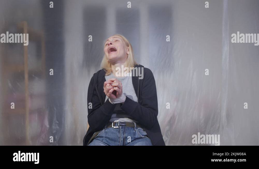 A female hostage is crying while sitting on a chair in an empty room ...