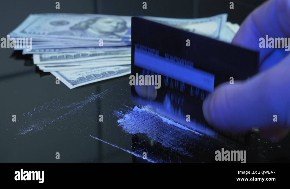 Addict makes lines of white drug powder on black background ...