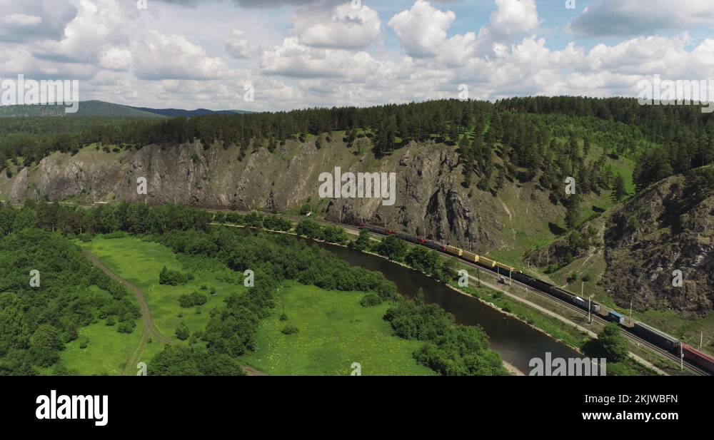 Freight long train carries with cargo carriages under the rock near ...