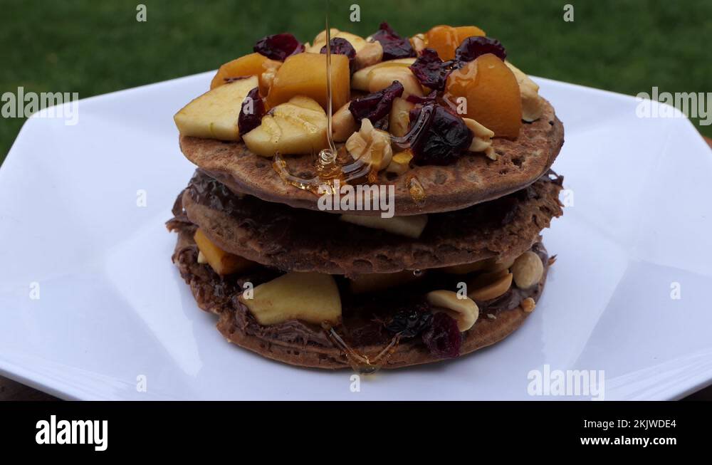 Honey dripping down a pancake with fruits and walnuts in slow motion 4k ...