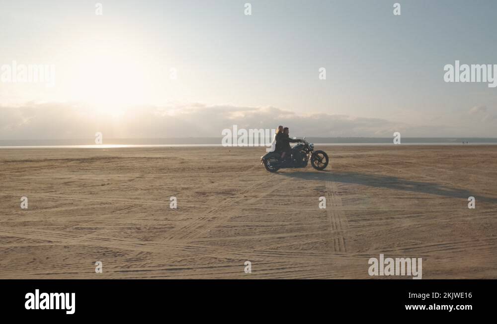 Guy with a girl ride on a motorcycle in the desert. Couple in love on ...