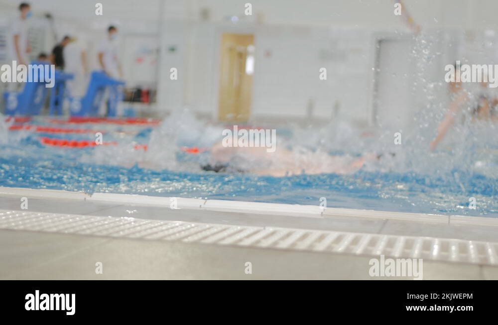 teenage swimmers start in the pool and swim past the camera. Swimming ...