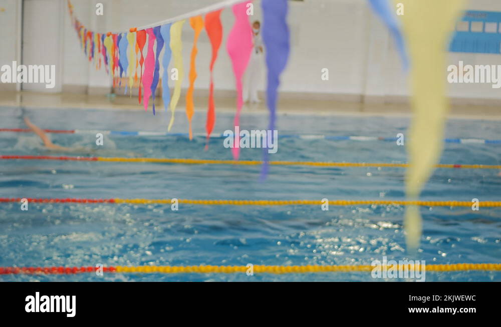 athletes swimmers swim in the pool. There are brightly colored flags ...