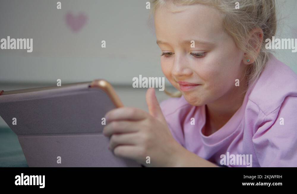 Little girl lying on bed and using tablet Stock Video Footage - Alamy