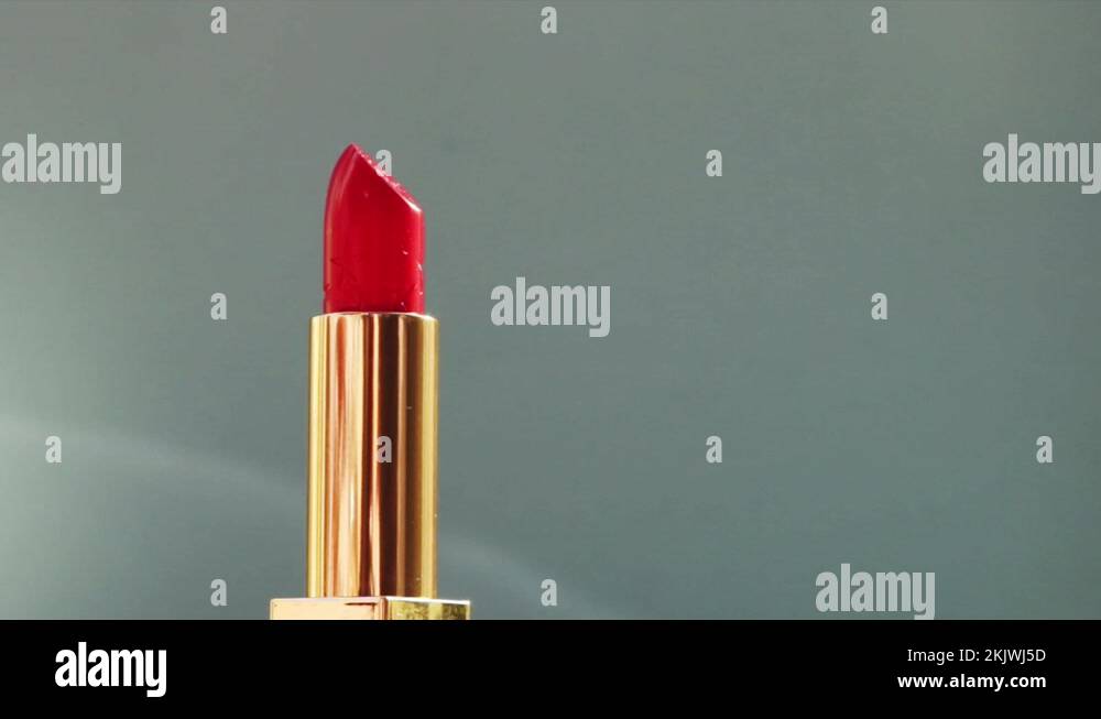 Luxe red lipstick in golden tube on colour background and shining light ...