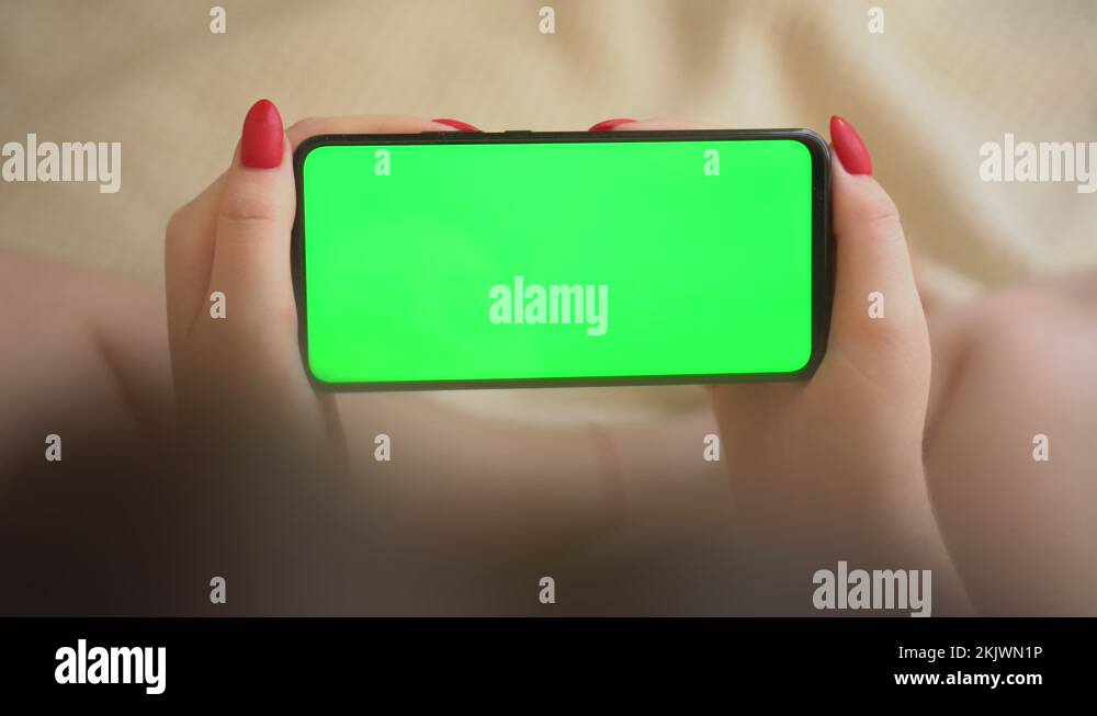 Back view over shoulder of young girl using smartphone with green ...