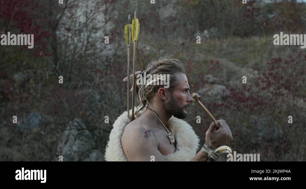 Wildman with bow and arrows hunting in nature. Side view of brutal ...