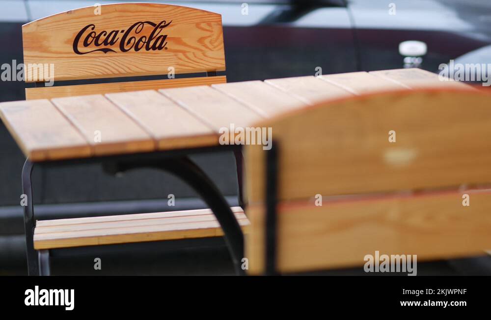 Wooden table and chairs of a street cafe with Coca Cola logo applied ...