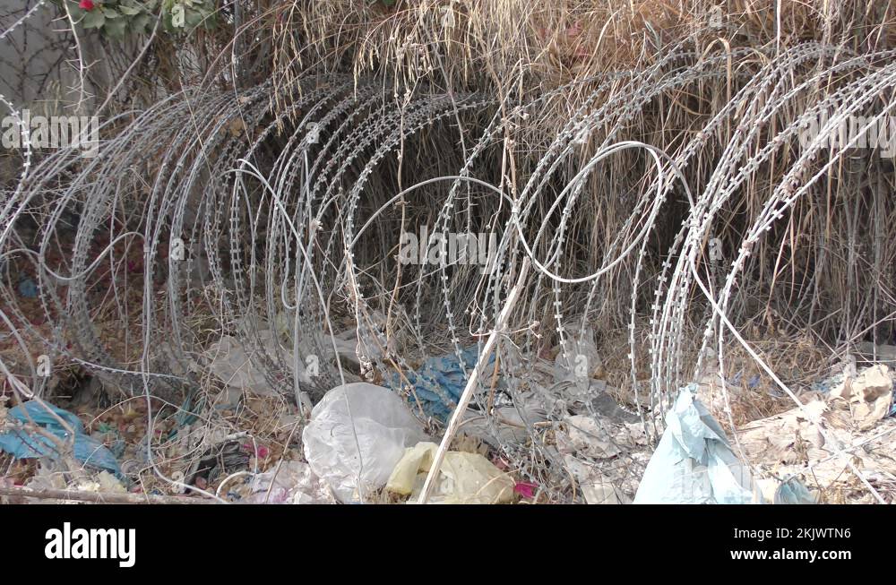 Plastic waste in a ditch of water with nylon barbed wire around secured ...