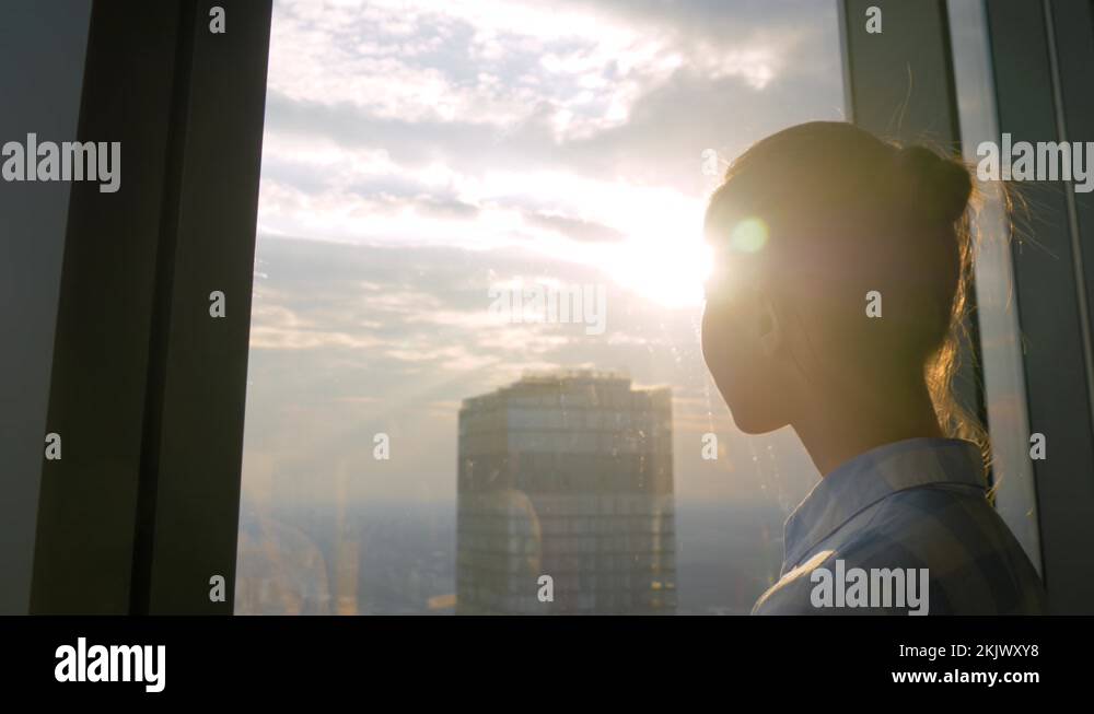 Woman looking at cityscape through window of skyscraper - sun lens ...