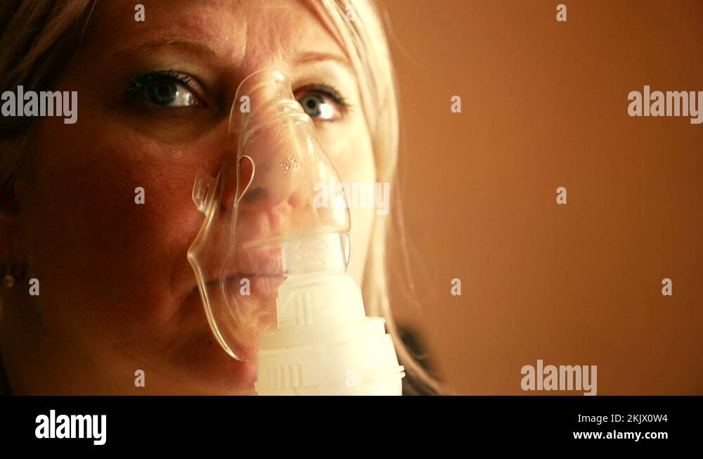 Close-up face of a woman breathing in an inhaler. Use a nebulizer and ...