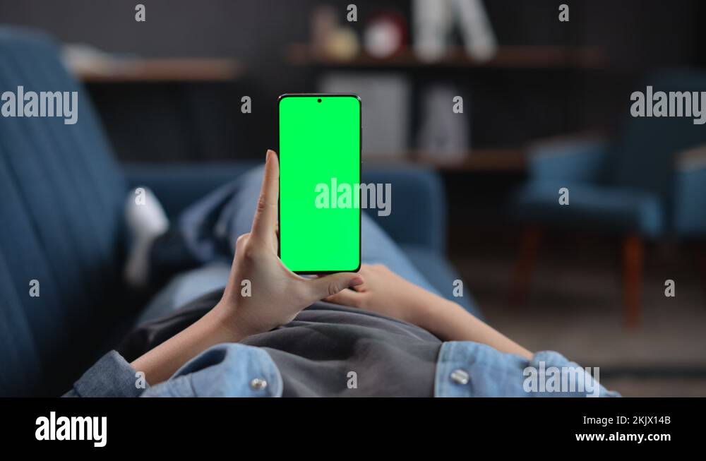 The woman is lying on a Coach in Living Room, holding Green Screen ...